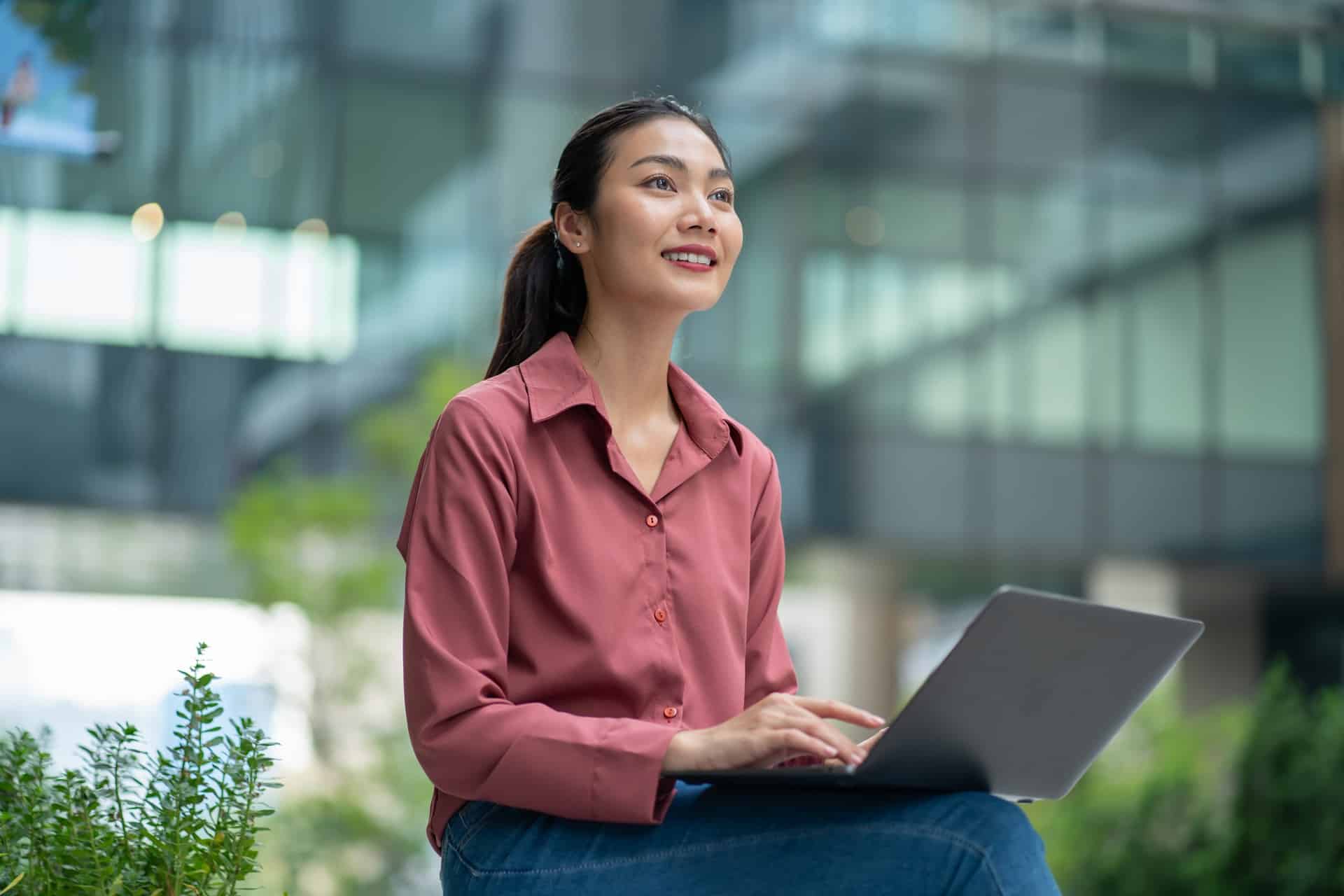 Business women working on laptop outdoors with green city background | ENGIE UK